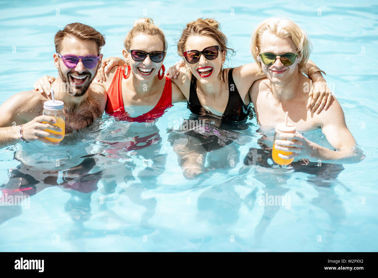 Portrait of a group of happy friends standing together in the swimming ...