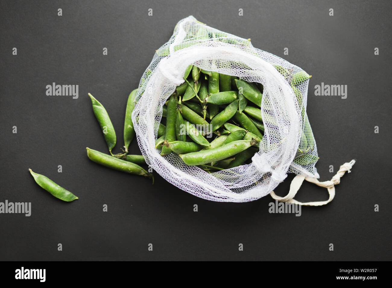 Reusable eco-friendly bag full of fresh seasonal pea pods . Taking care ...