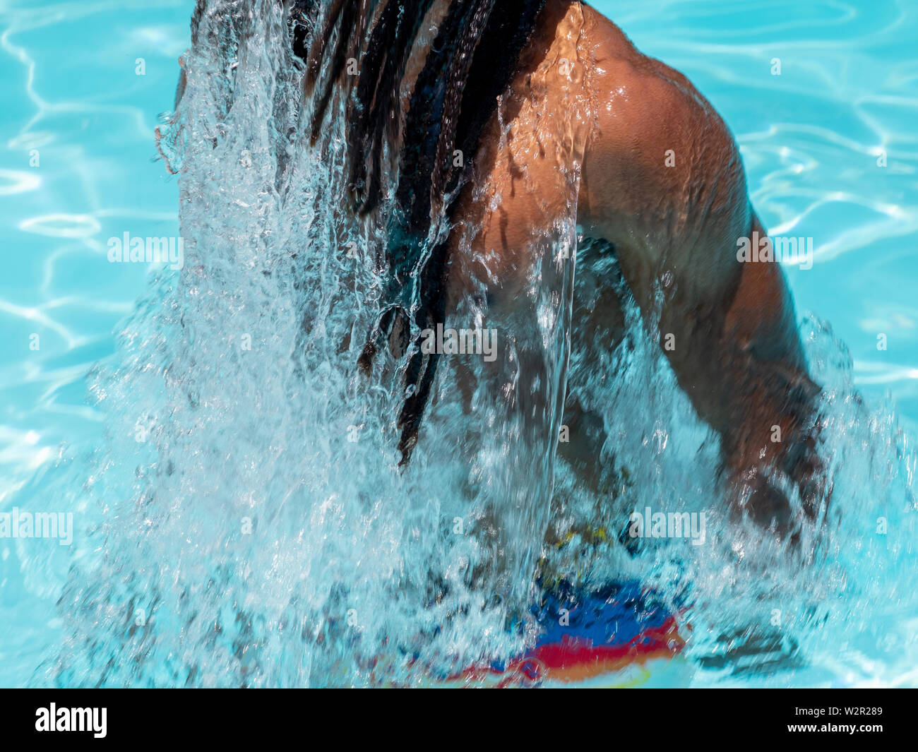 Black man with afro hair and dreadlocks comes out of the pool splashing ...