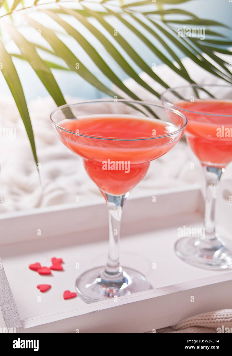 Two pink coral fresh exotic alcoholic cocktail in clear glasses under ...