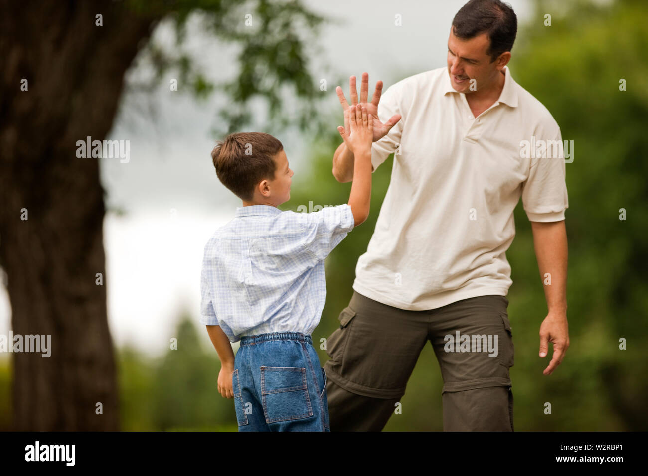Young boy high fiving his father Stock Photo - Alamy
