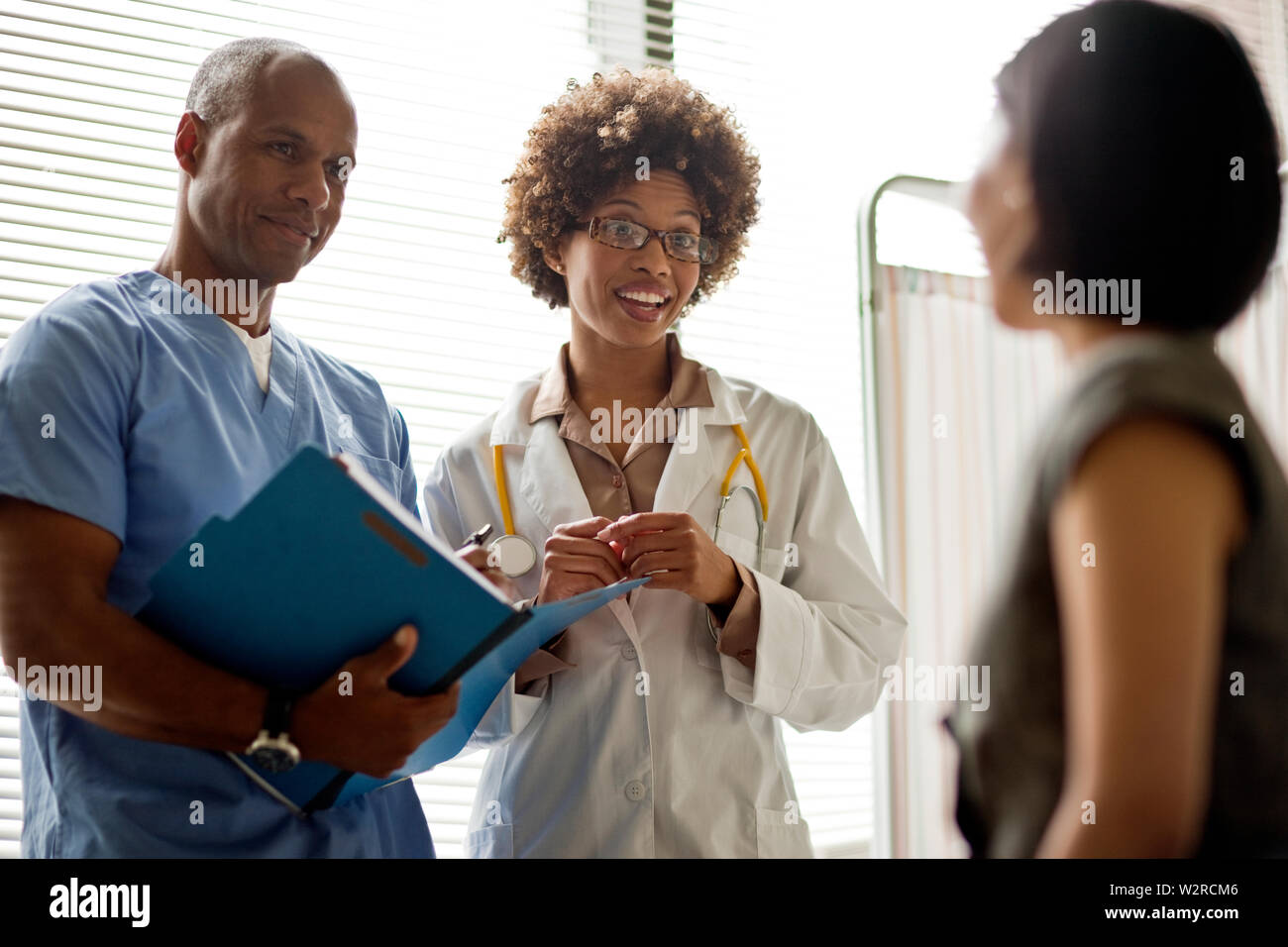 Female doctor and male nurse talking to patient Stock Photo - Alamy