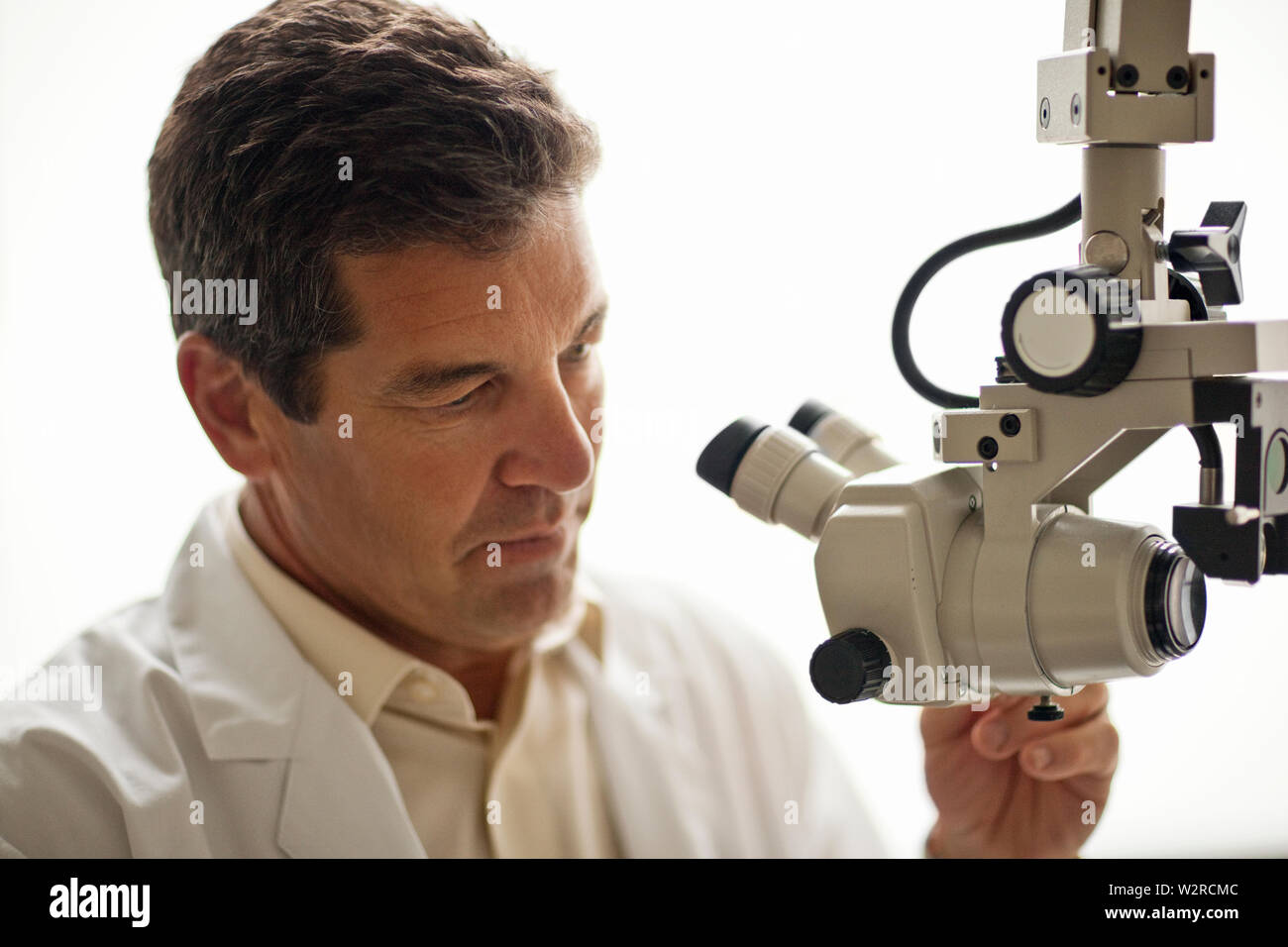 Male doctor looking at something through a microscope Stock Photo - Alamy