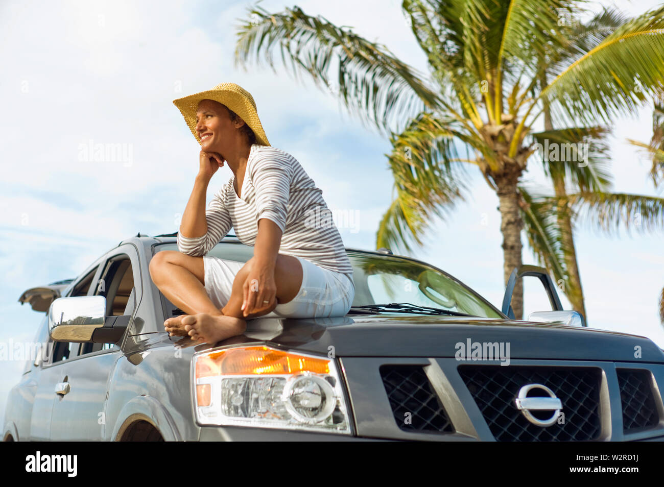 Woman sitting on bonnet of car in sunshine Stock Photo - Alamy