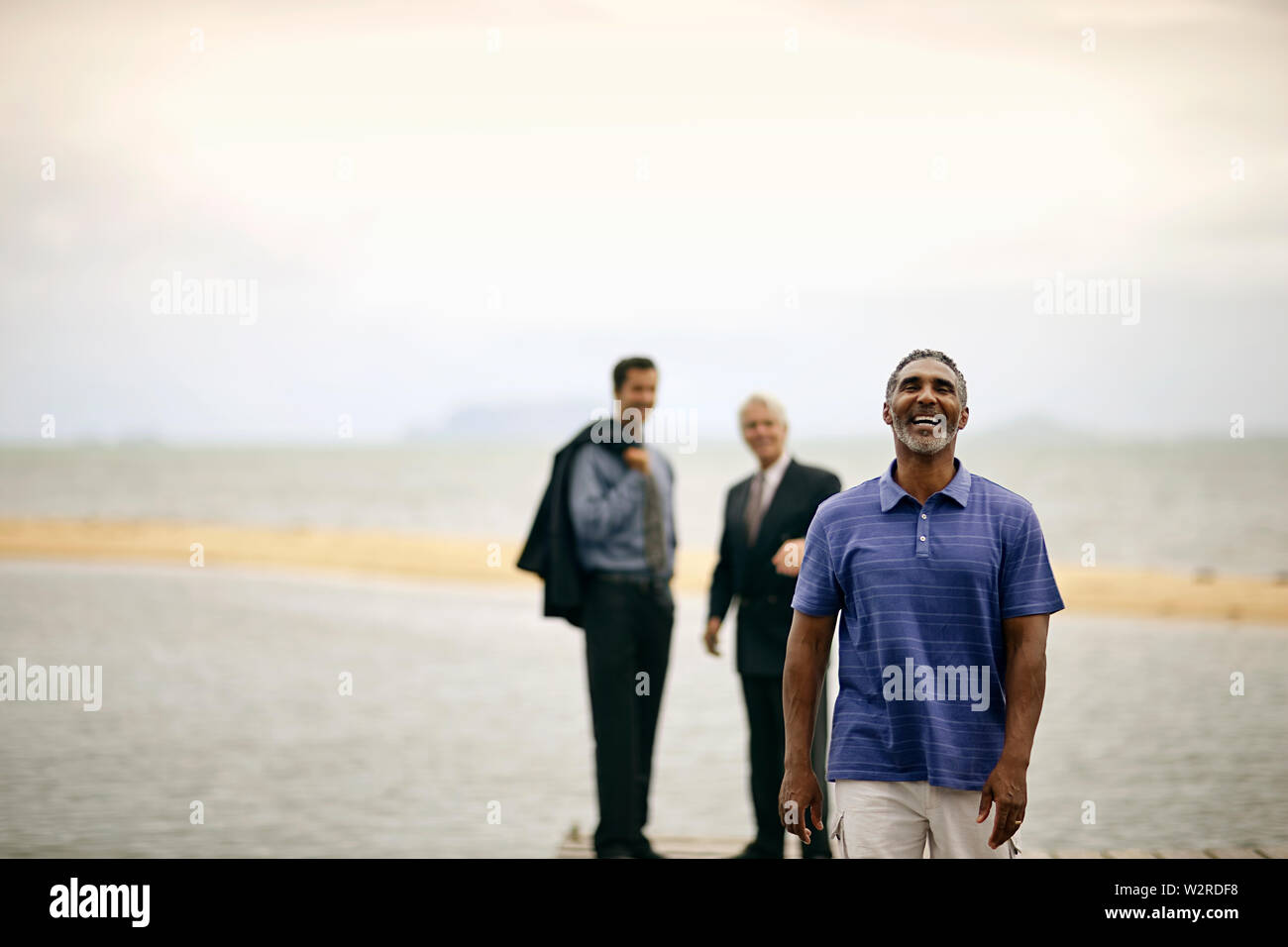 Laughing man walking away from two businessmen Stock Photo - Alamy