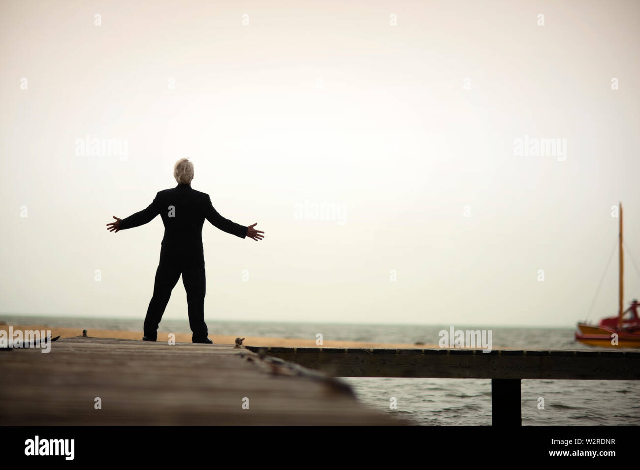 Mature businessman standing on a jetty with his arms outstretched Stock ...