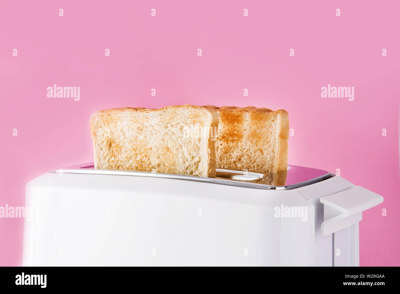 Toasted toast bread in white toaster on pink background Stock Photo - Alamy