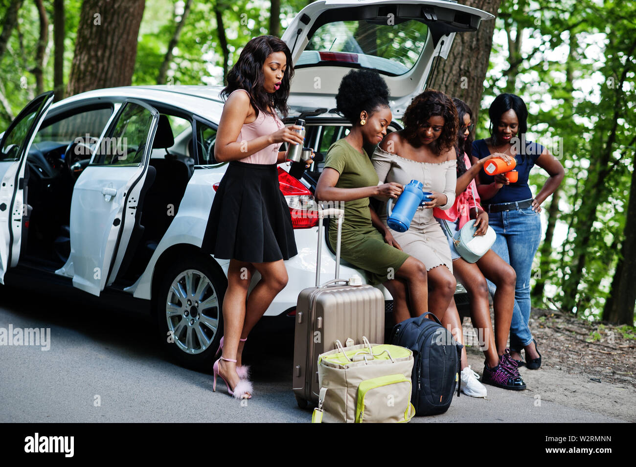 Group of five happy african american traveler girls sitting in car open ...