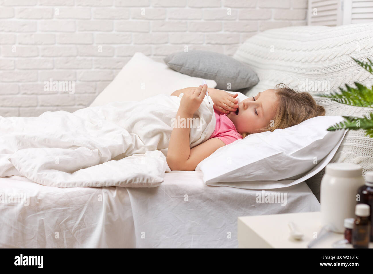 Sick little child girl lying in bed with thermometer. Cold flu season ...