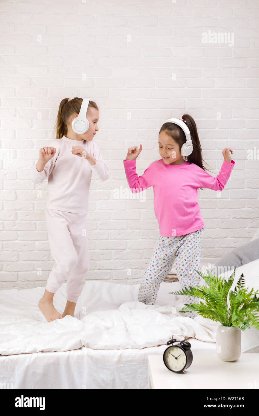 little children girls listening to the music with the headphones and ...