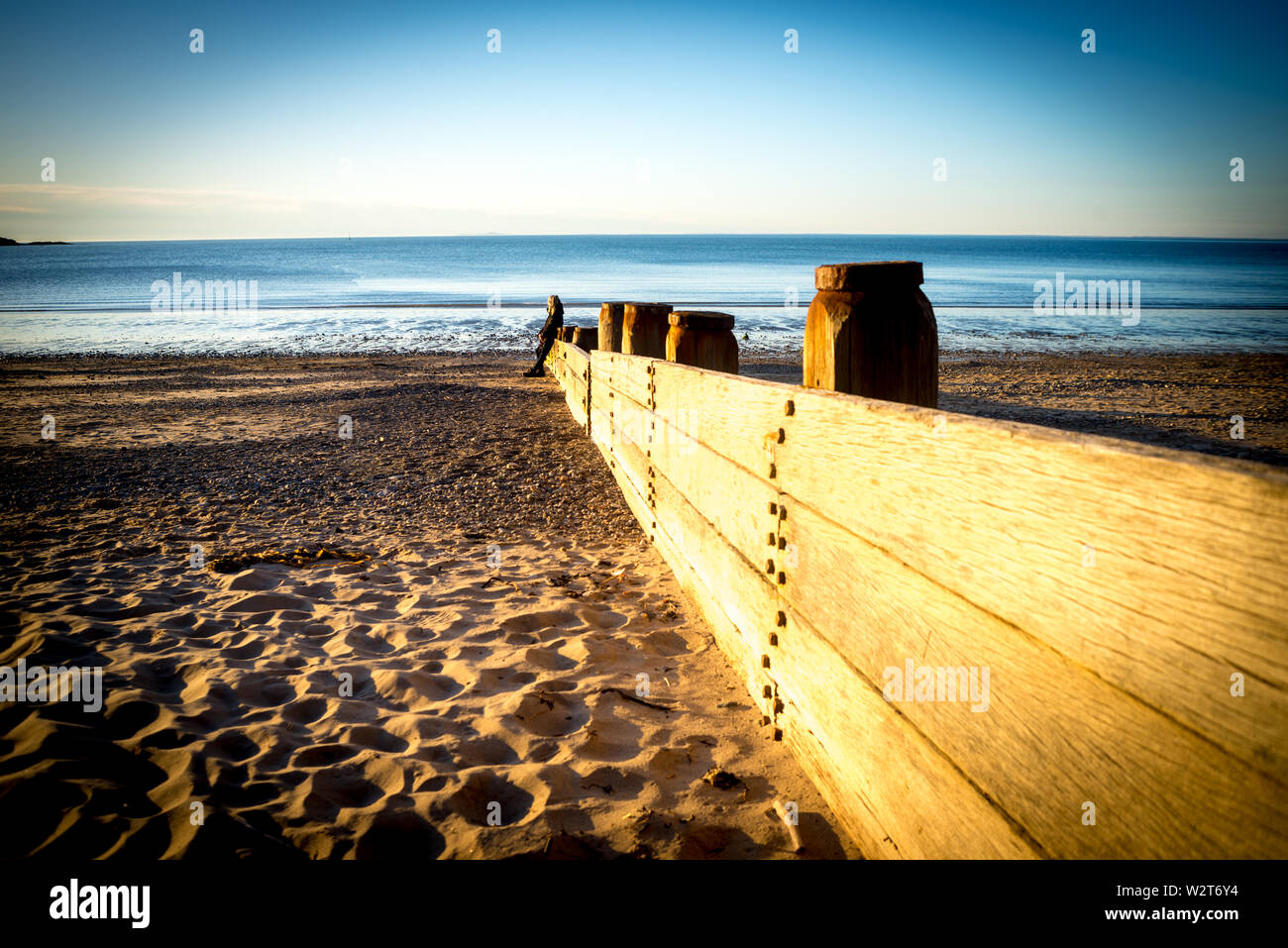 Woman at end of groin on beach Stock Photo - Alamy