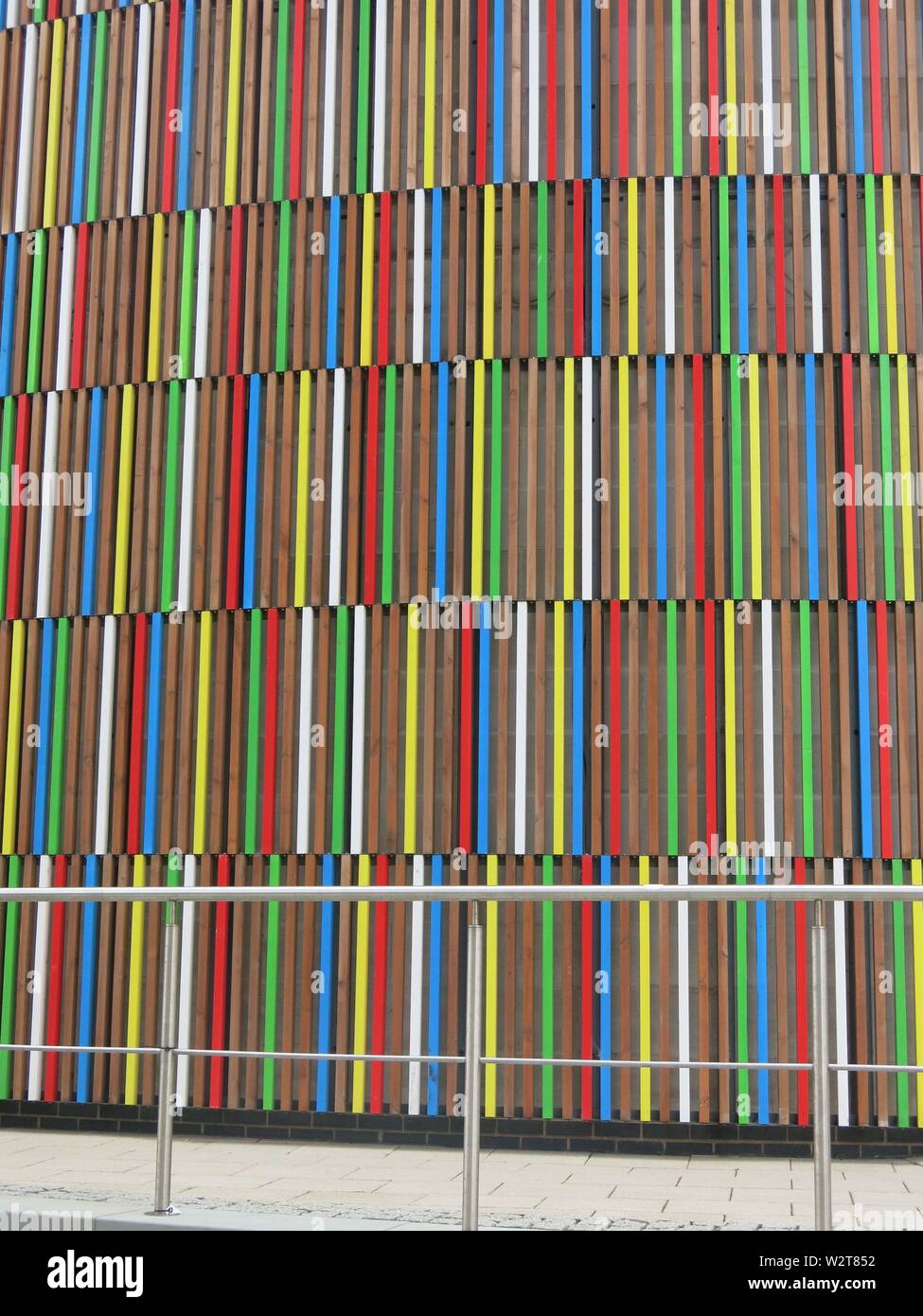 Multi-coloured stripes in rows of cladding on the wall of a modern ...
