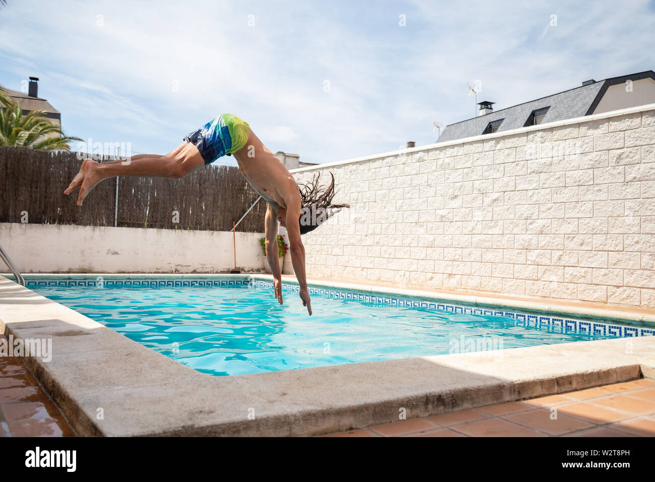 Young fitness man jumping into the water in the pool one day of summer ...