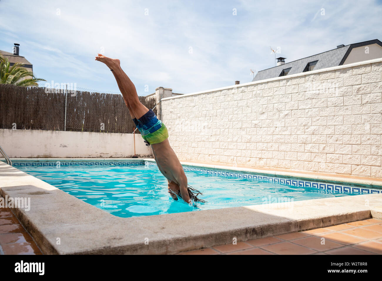 Young fitness man jumping into the water in the pool one day of summer ...