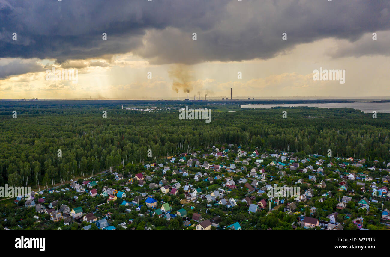 village in the forest, and on the horizon a Smoking plant and smoke is ...