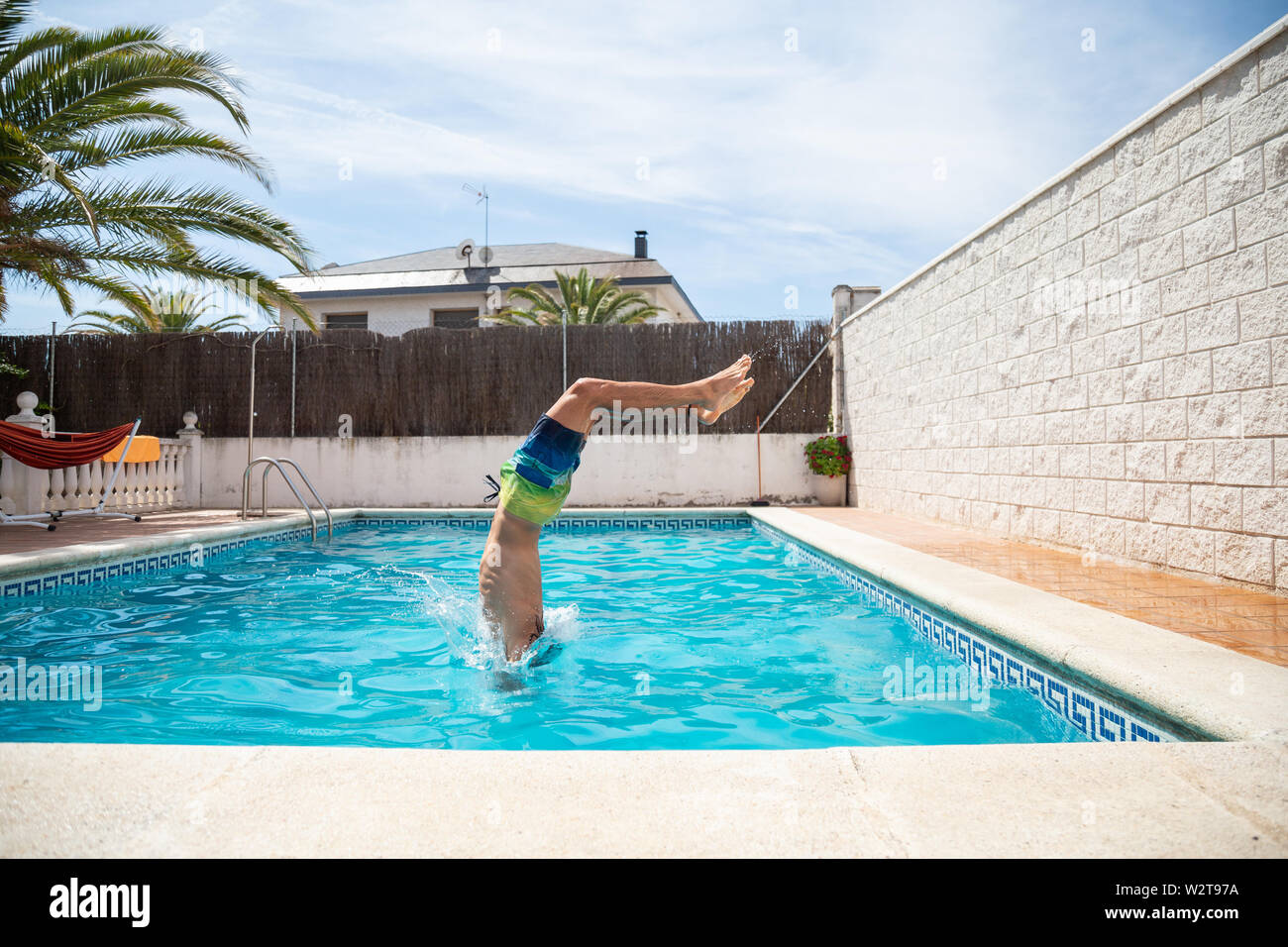 Young fitness man jumping into the water in the pool one day of summer ...