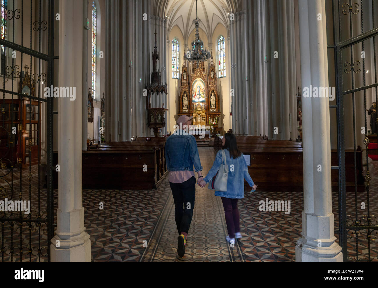 two young people, couple holding hands walking in a church indoors ...
