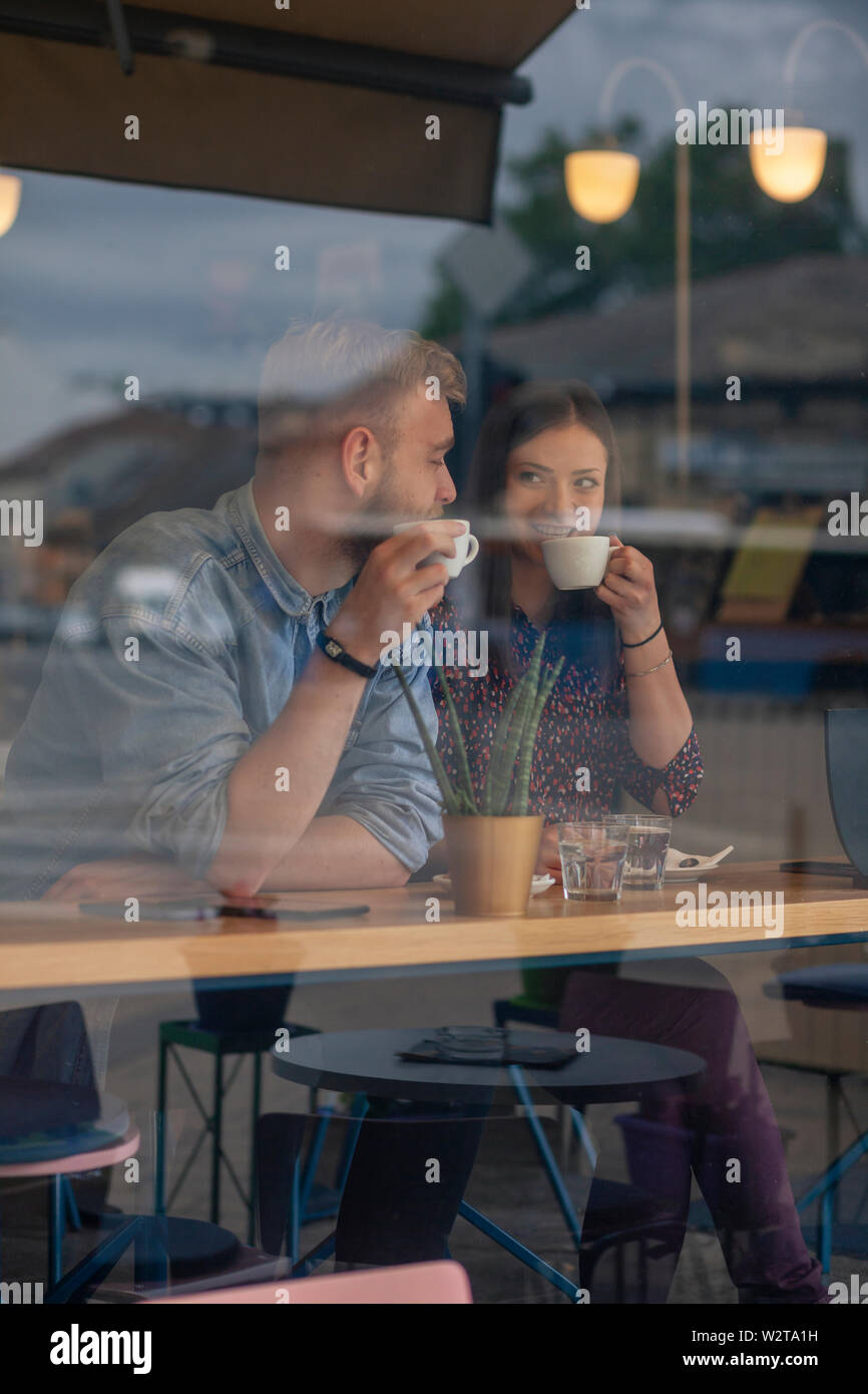 two friends sitting together in a cafe, drinking coffee. shot thought ...