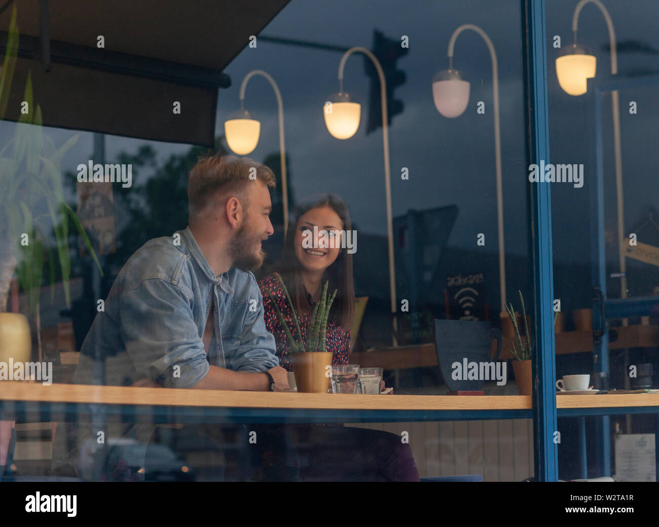 two friends talking in a cafe. Shot through window Stock Photo - Alamy