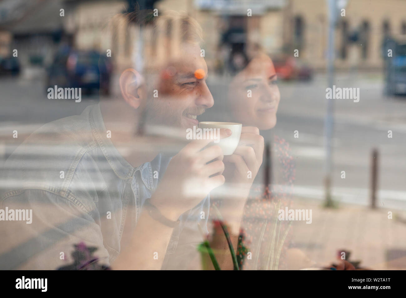 two friends drinking coffee in a cafe. Shot thought window with ...