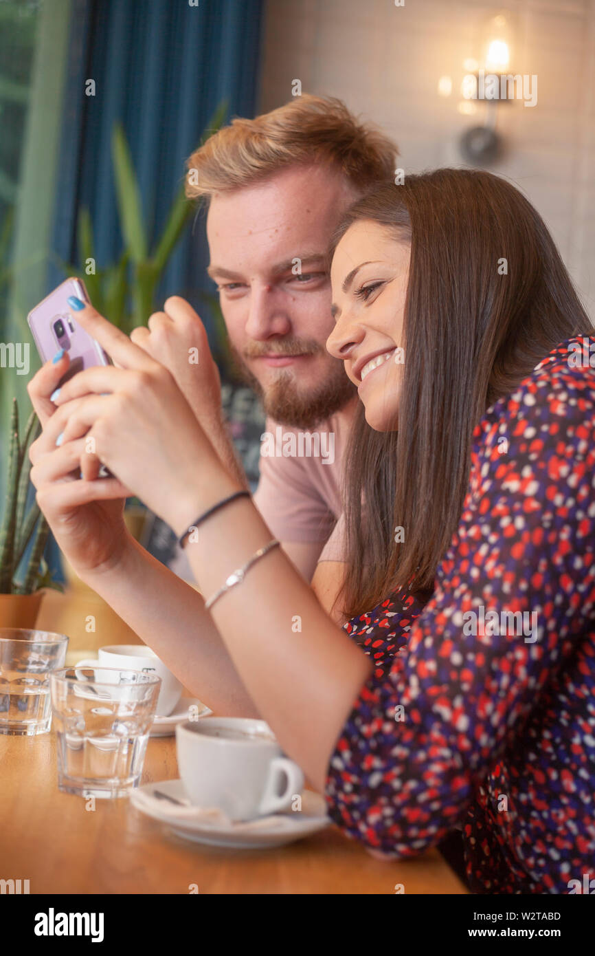 two friends sitting together, happy while looking at a phone screen ...