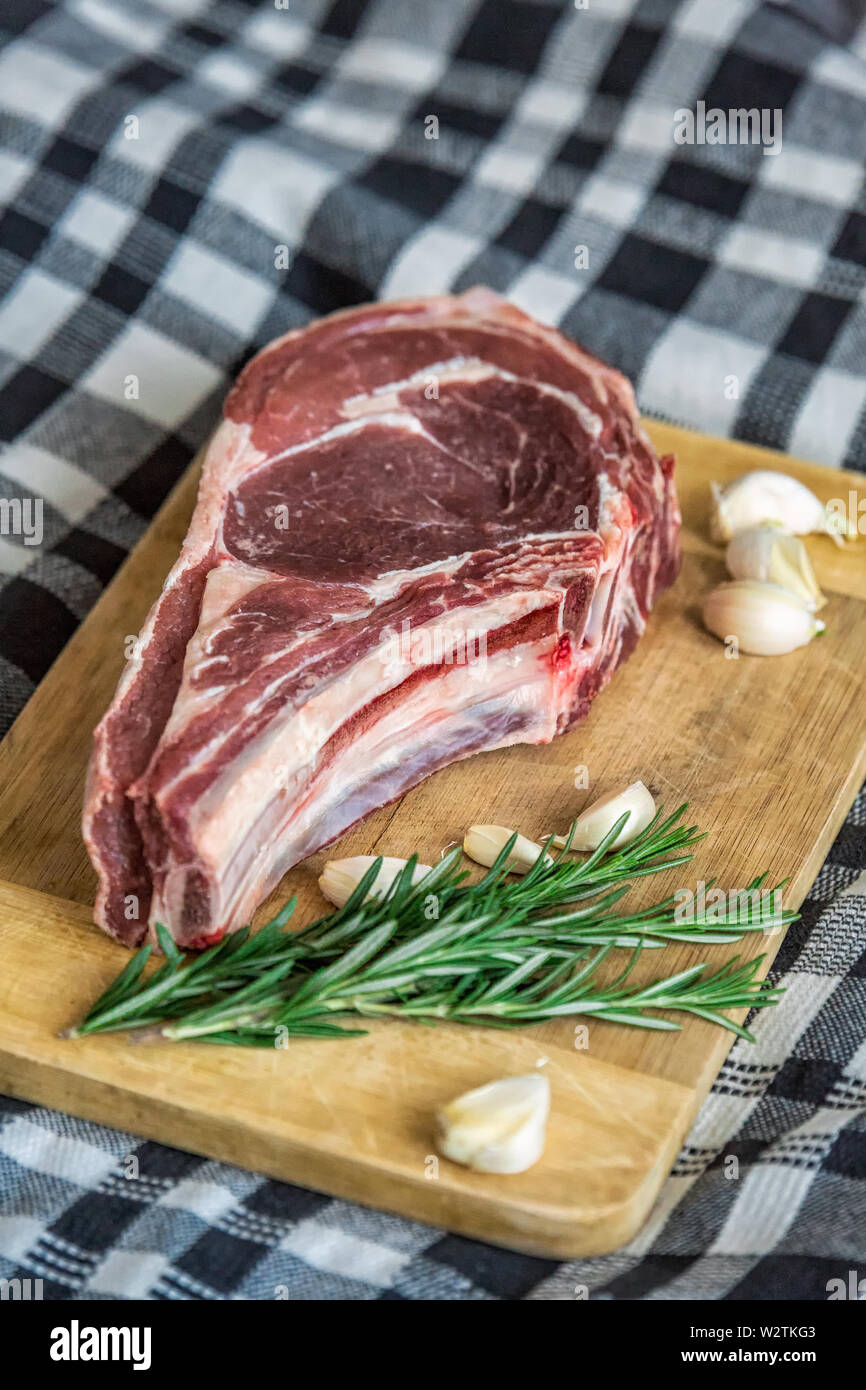 Raw meat cut with hyme and garlic and rosemary on cutting board, top ...