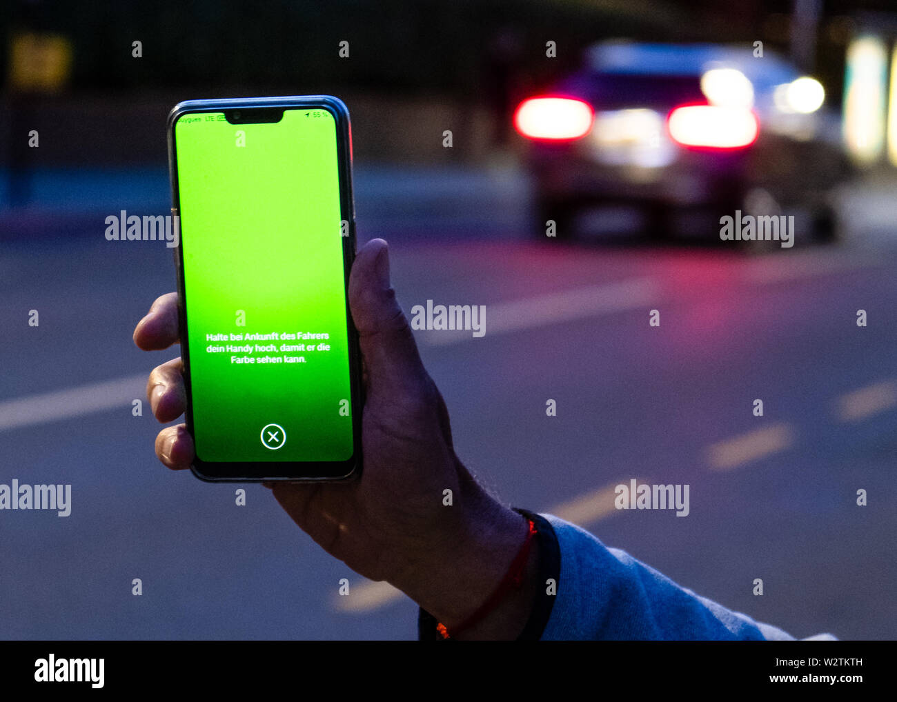 Detail of a man holding up a smartphone with the Uber transport color ...