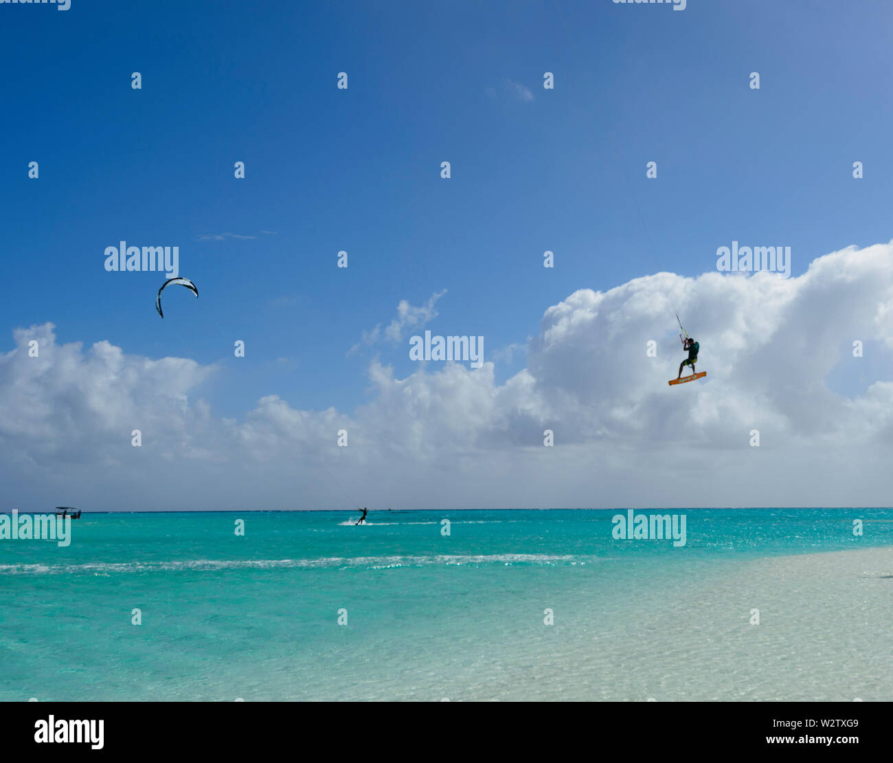 Tourists kitesurfing jumping in the air and taking off on the turquoise ...