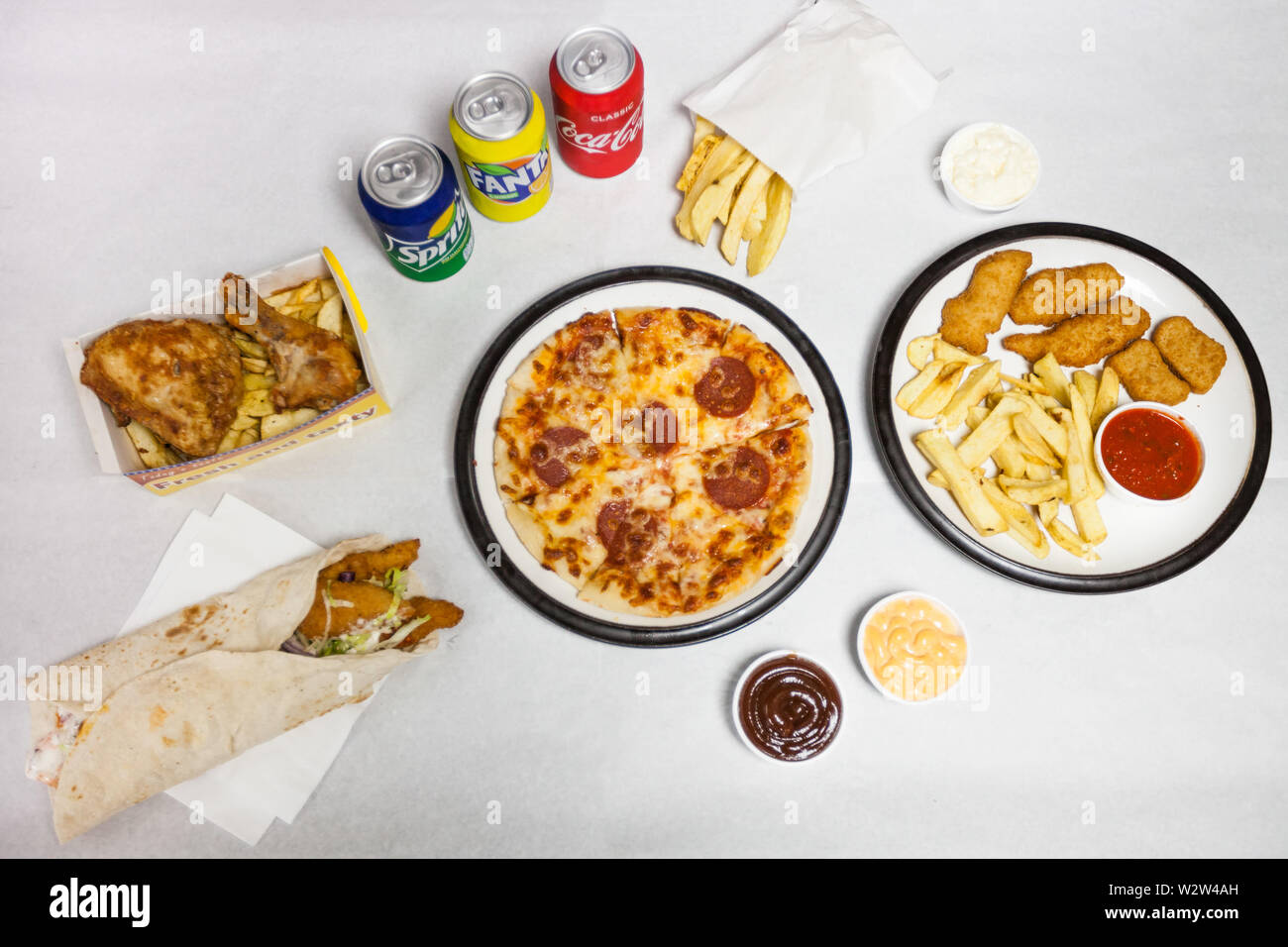 Selection of unhealthy take way fast-food presented on table covered ...