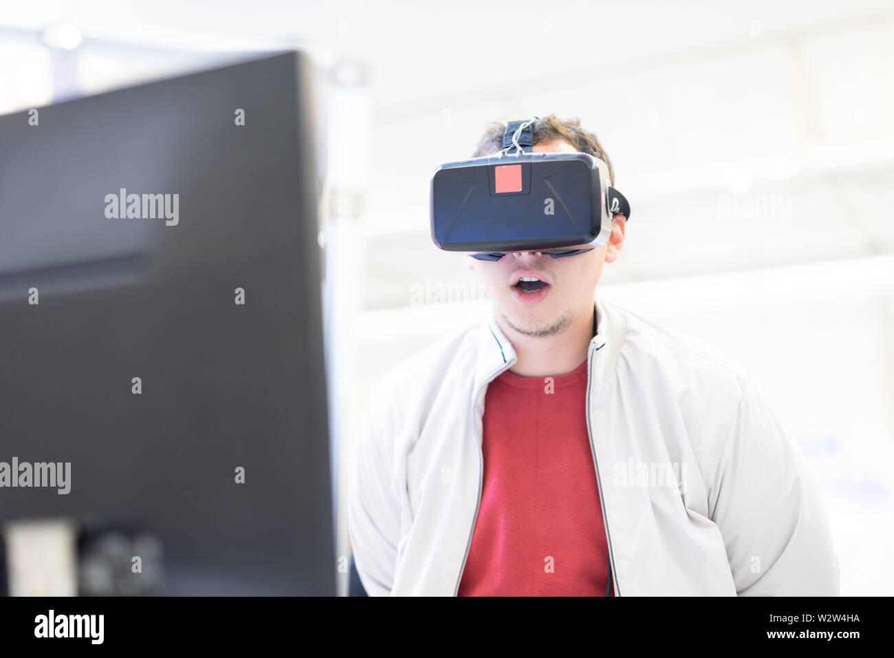 Young man wearing virtual reality headset and gesturing while sitting ...