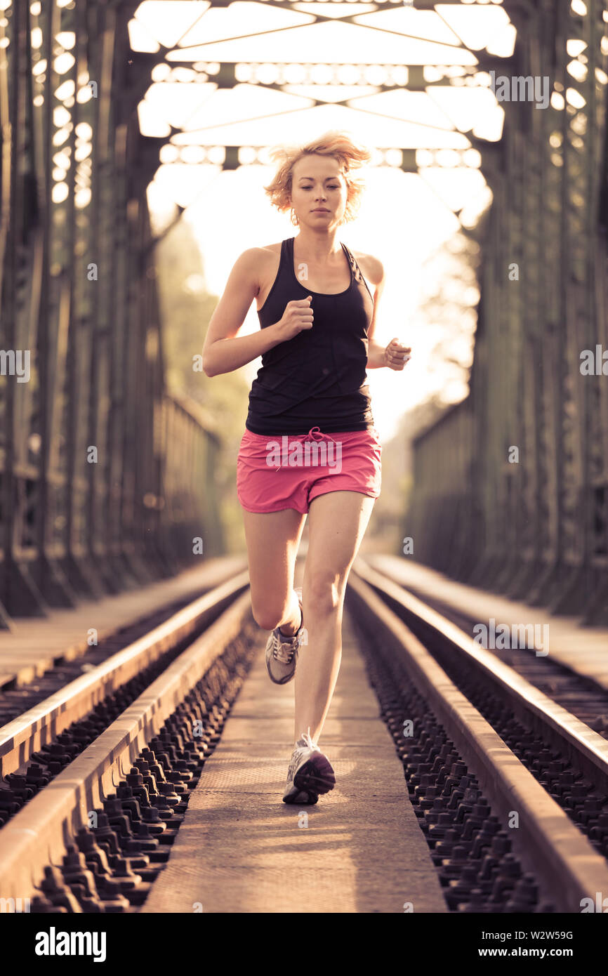 Active sporty woman running on railroad tracks Stock Photo - Alamy