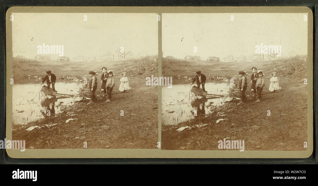 Group of children playing around water hole strewn with refuse ...