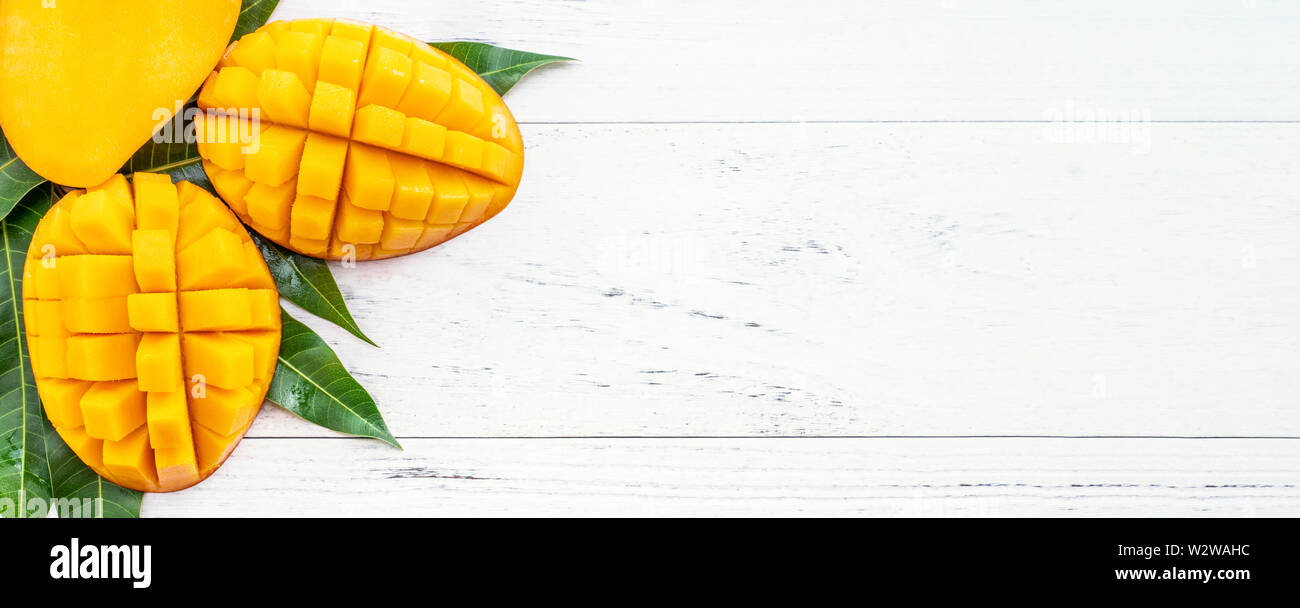 Beautiful chopped mango with green leaves on bright white color timber ...