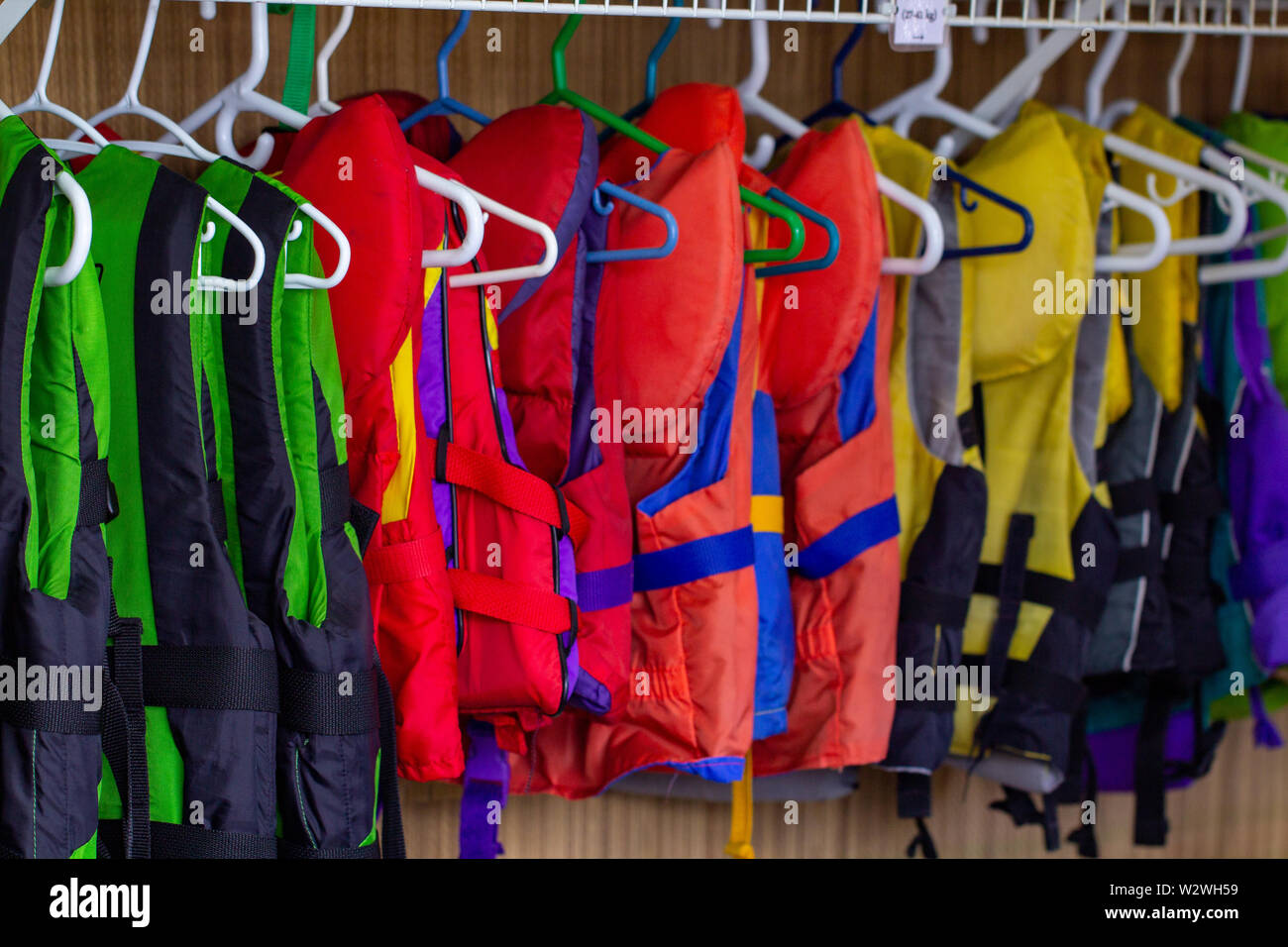 A bunch of life jackets hung up on a rack Stock Photo - Alamy