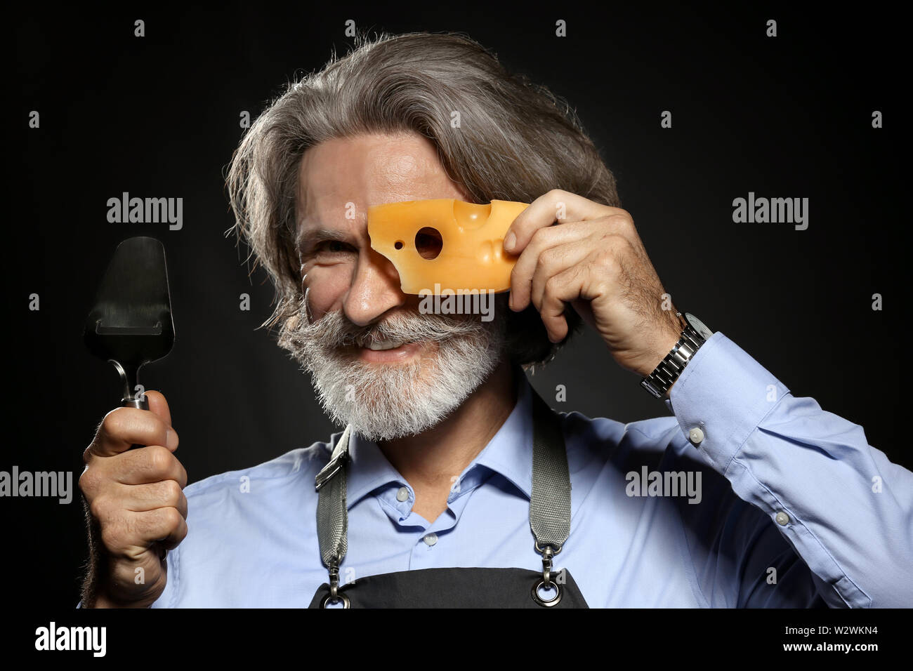 Male owner of cheese store on dark background Stock Photo - Alamy