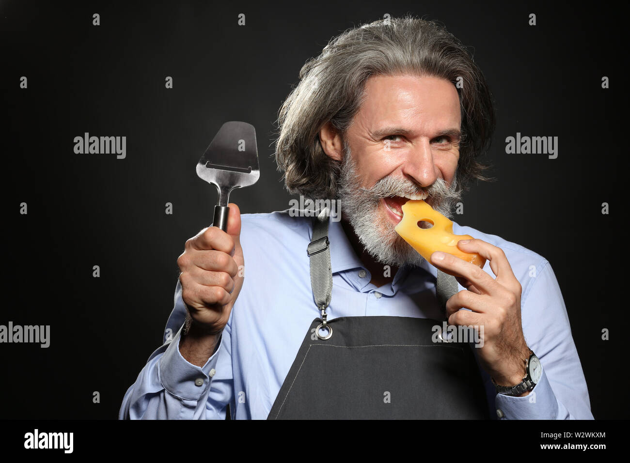 Male owner of cheese store on dark background Stock Photo - Alamy