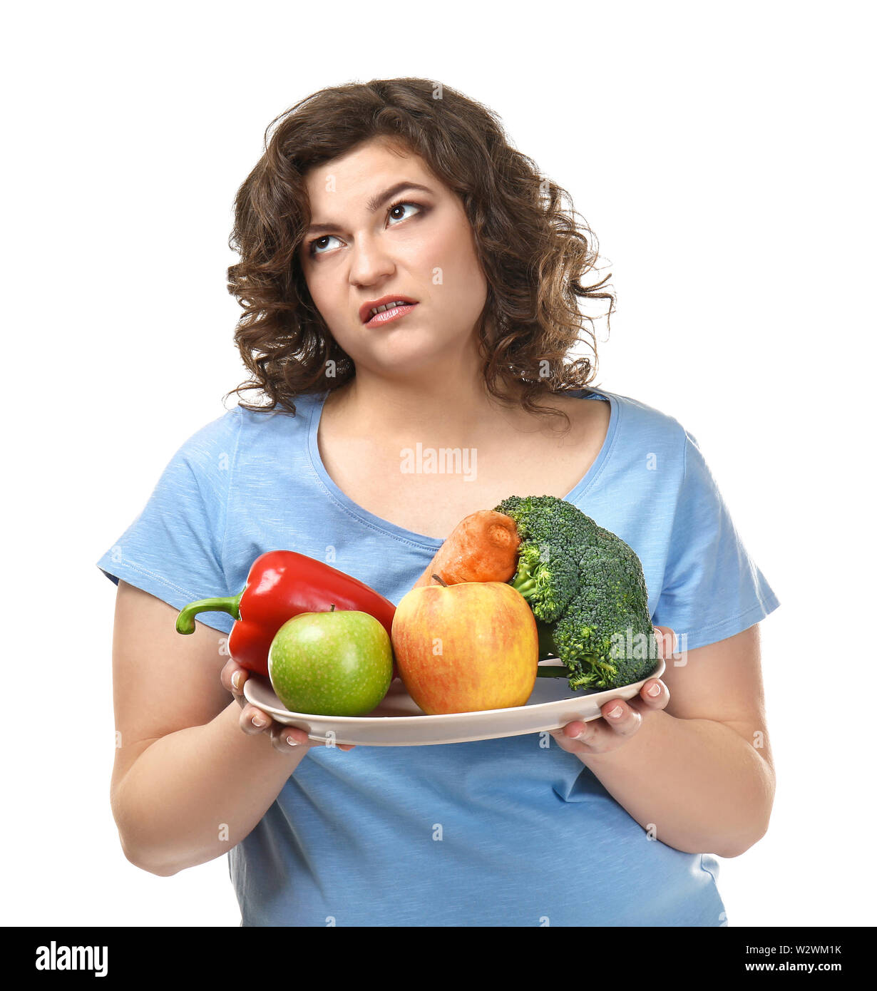 Displeased overweight woman with fruit and vegetables on white ...