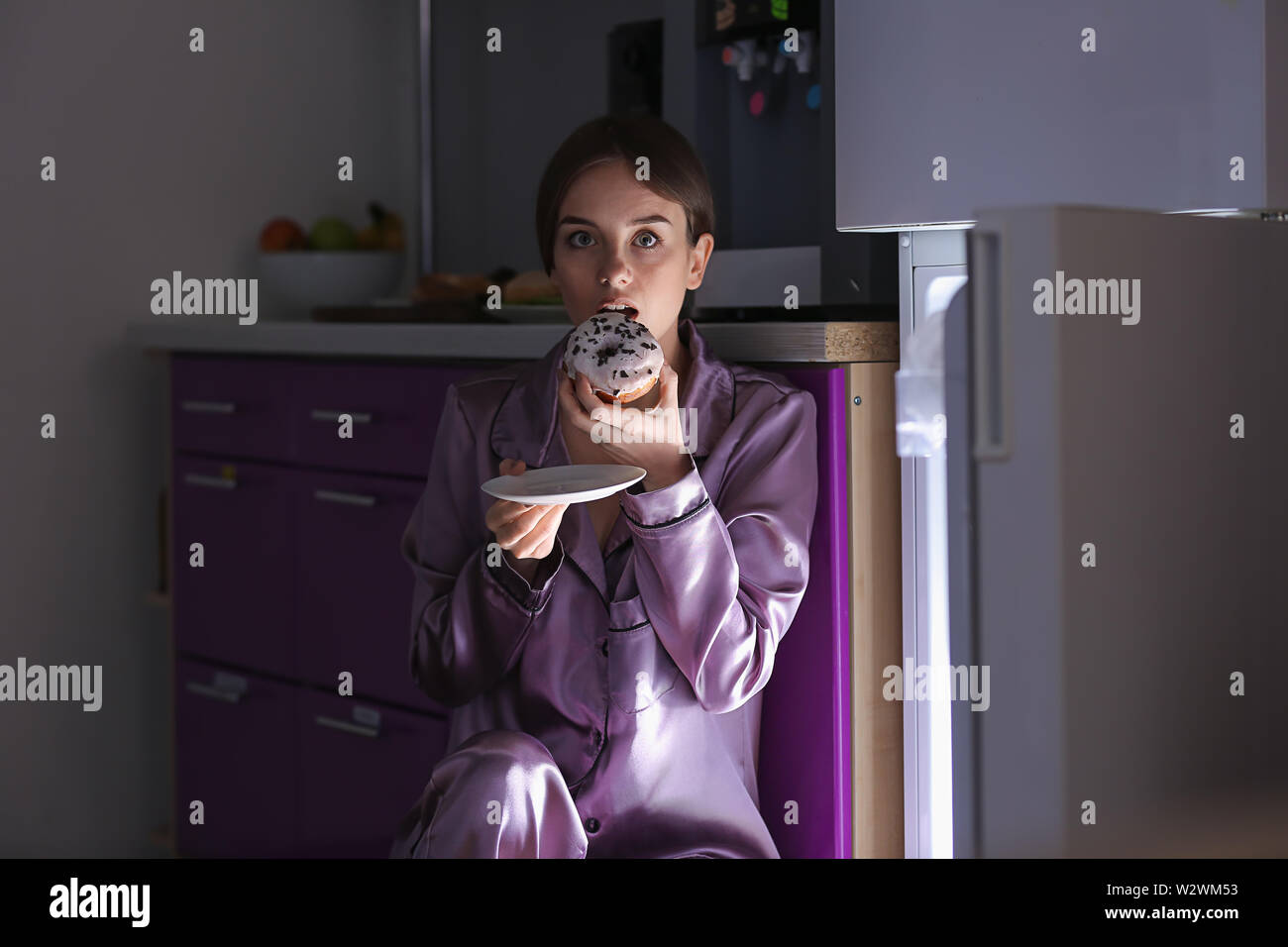 Afraid woman caught in the act of eating tasty unhealthy food near ...