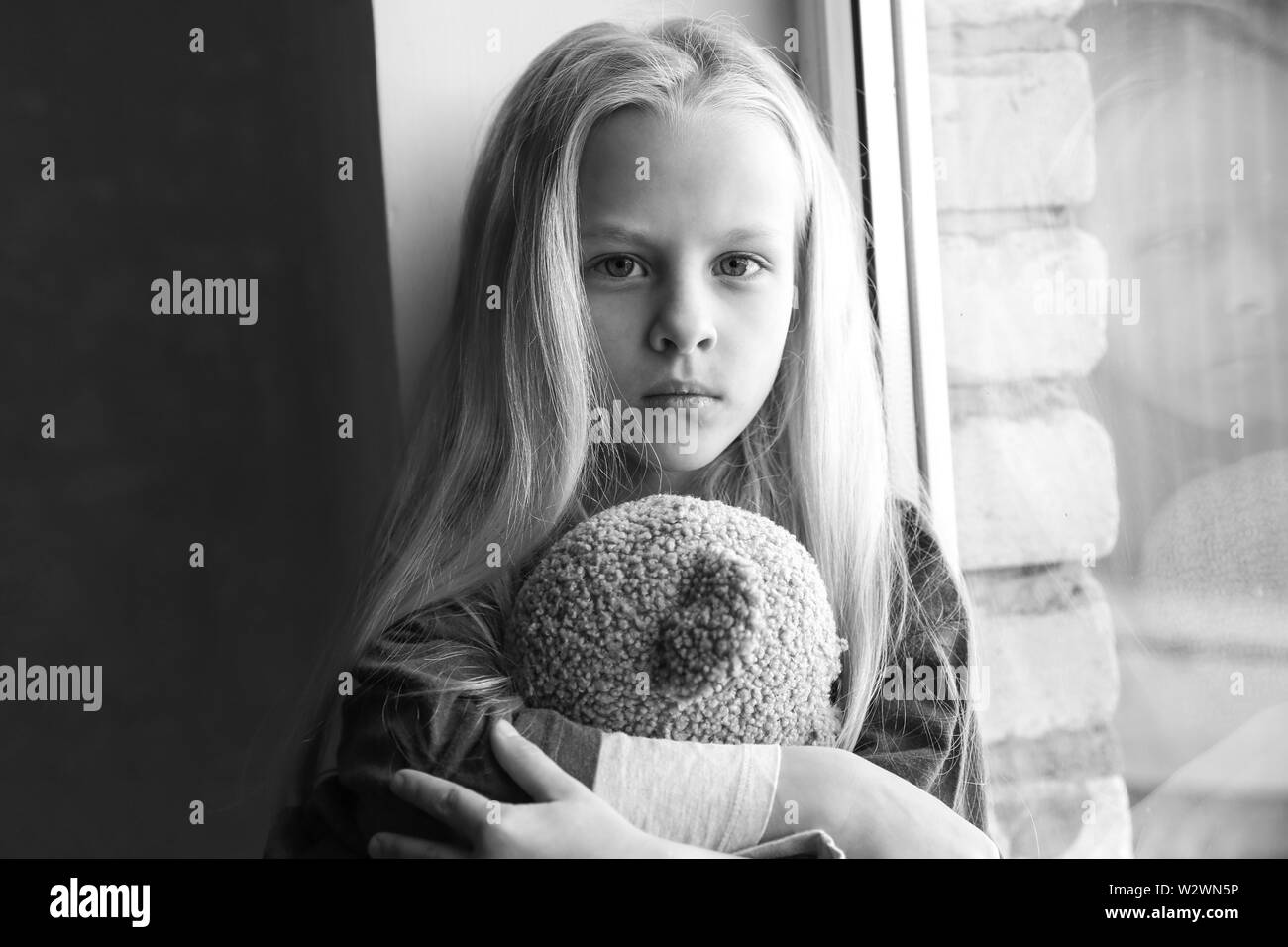 Homeless little girl with teddy bear sitting on window sill Stock Photo ...