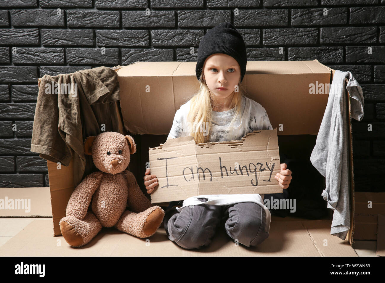 Homeless little girl begging for food indoors Stock Photo - Alamy