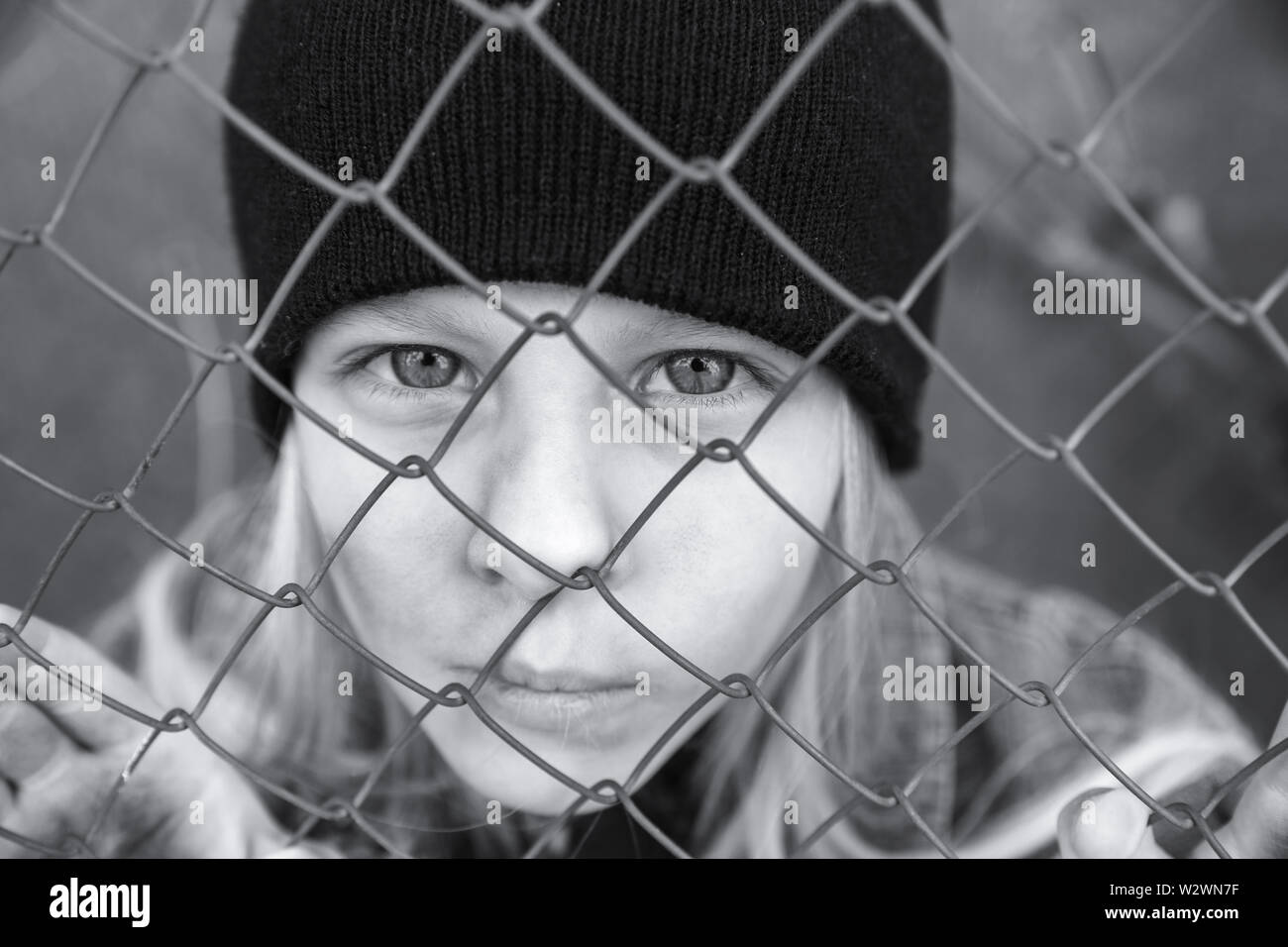 Homeless little girl standing behind mesh outdoors Stock Photo - Alamy