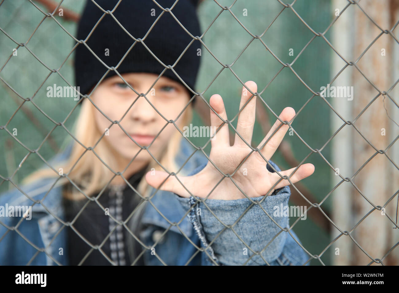 Homeless little girl standing behind mesh outdoors Stock Photo - Alamy