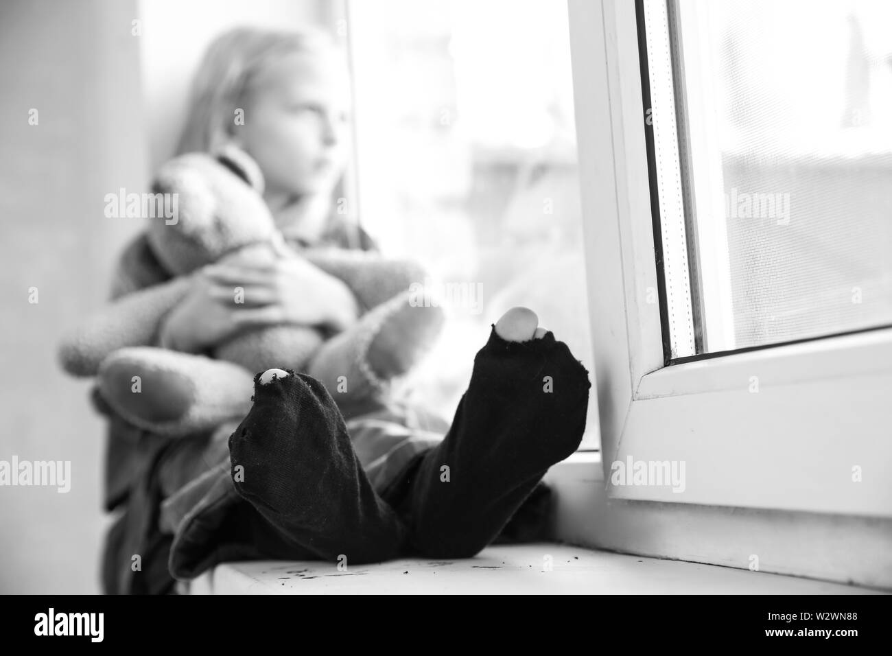 Homeless little girl sitting on window sill Stock Photo - Alamy
