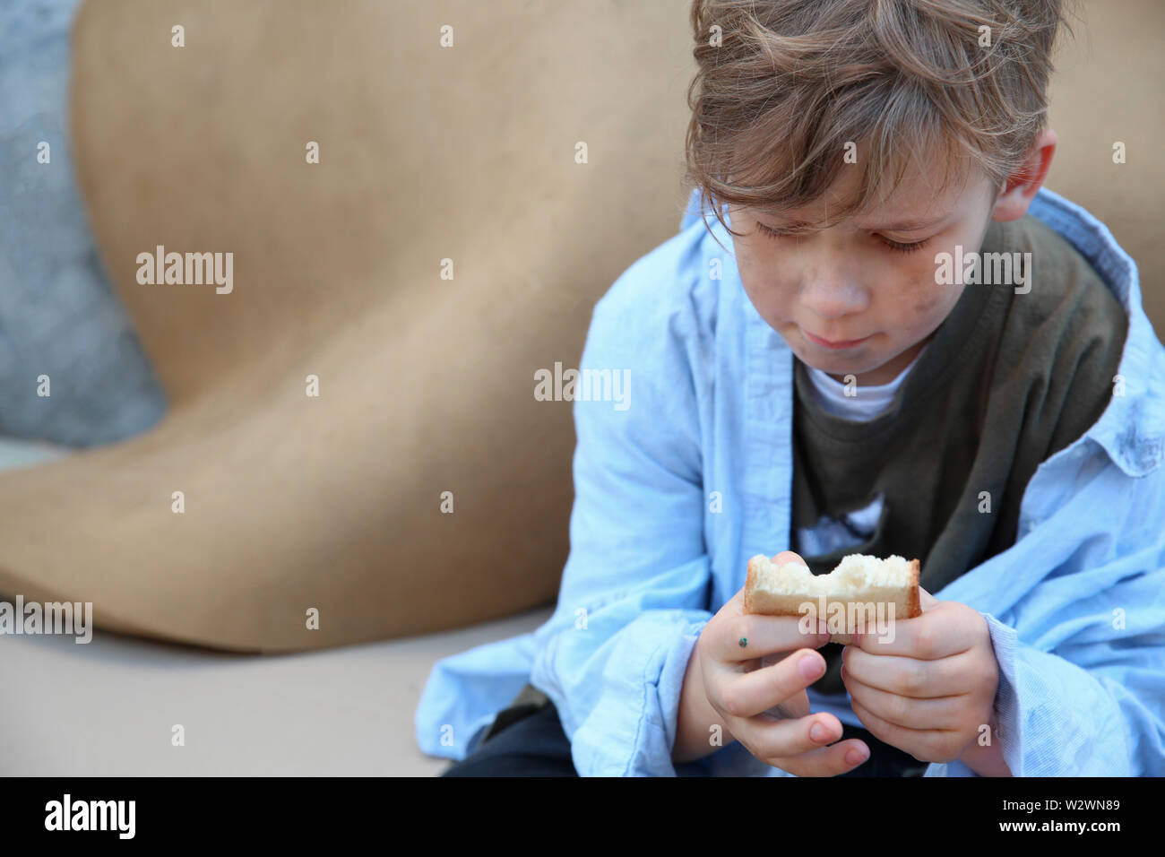 Homeless little boy with bread outdoors Stock Photo - Alamy