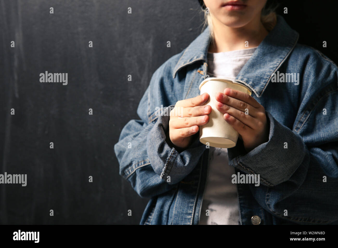 Homeless little girl with cup on dark background Stock Photo - Alamy