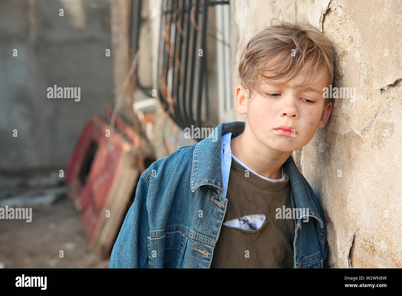 Homeless little boy near wall outdoors Stock Photo - Alamy