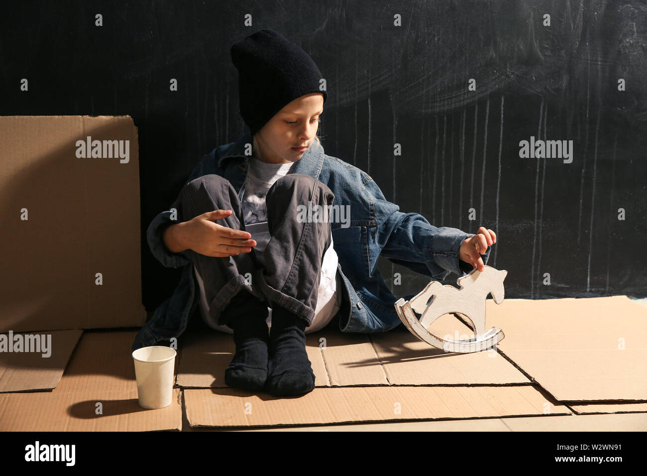 Homeless little girl playing with toy indoors Stock Photo - Alamy
