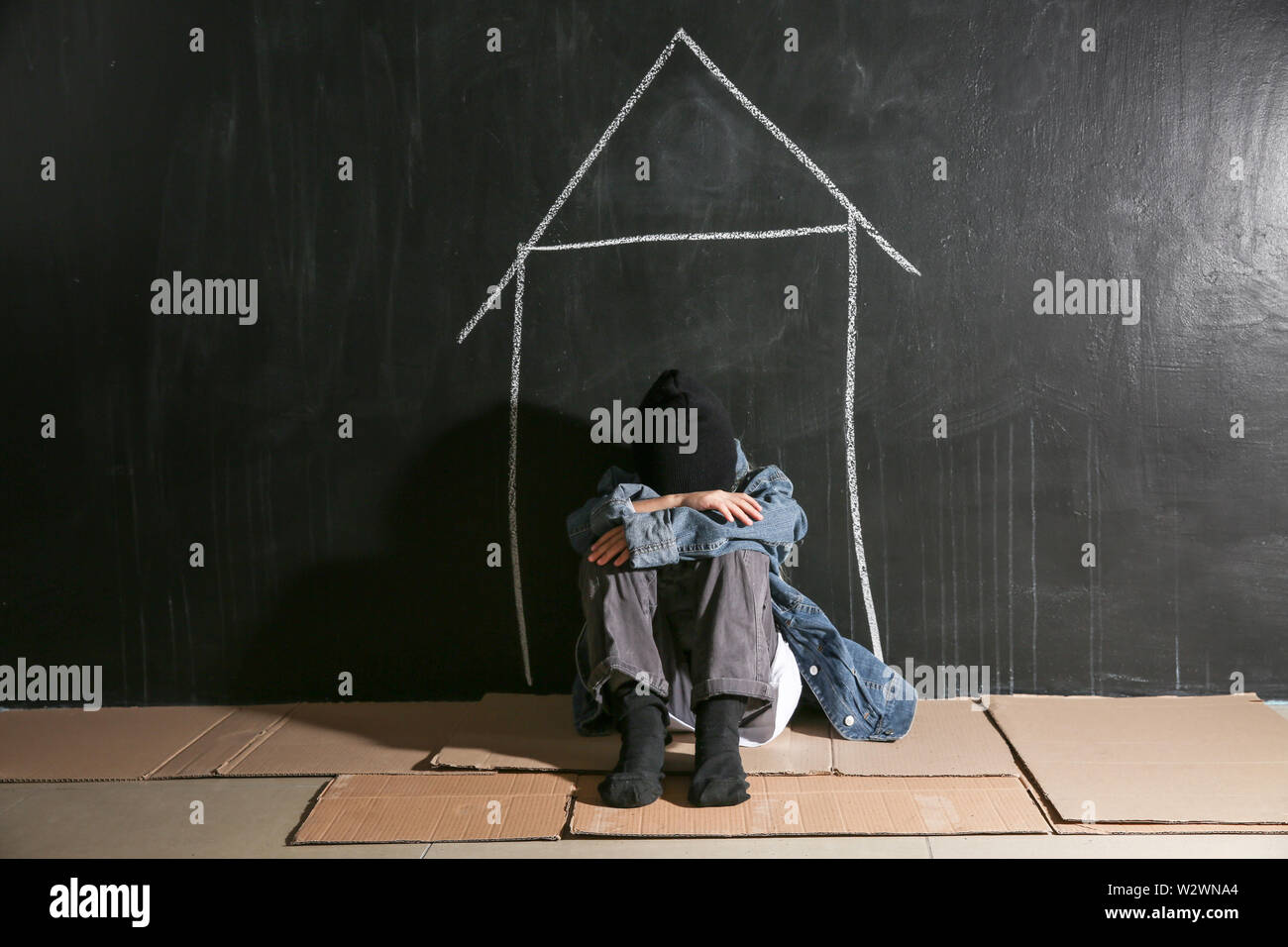 Homeless little girl sitting on floor near dark wall Stock Photo - Alamy