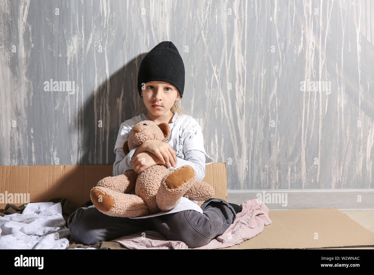 Homeless little girl with teddy bear sitting on floor near wall Stock ...