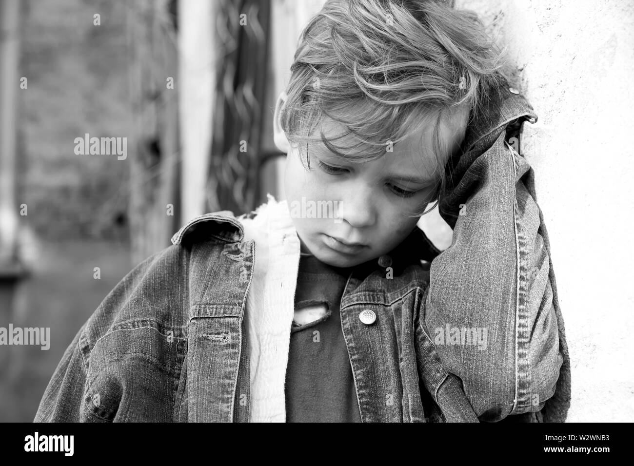 Homeless little boy near wall outdoors Stock Photo - Alamy